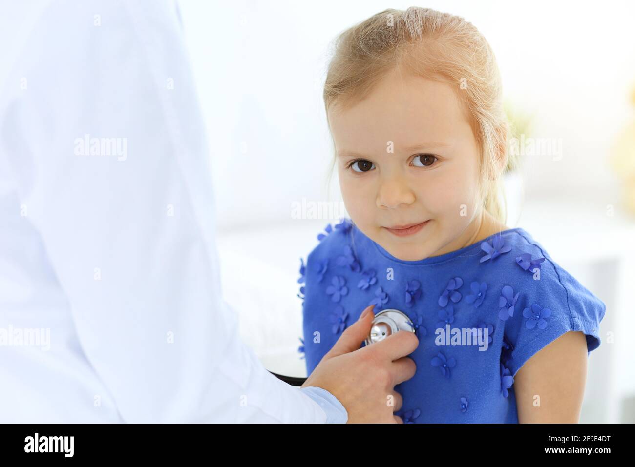 Doctor examining a little girl by stethoscope. Happy smiling child ...