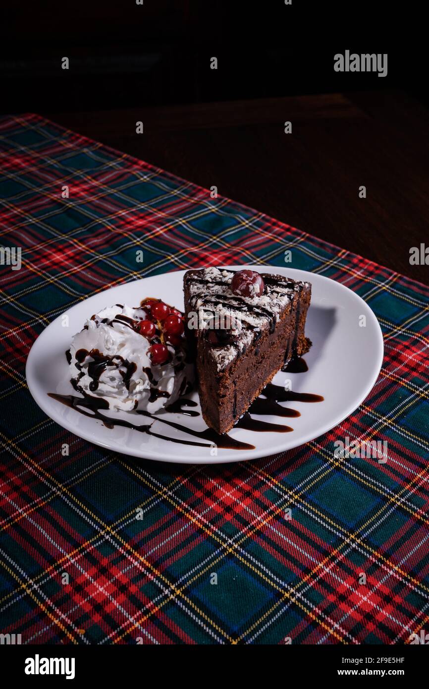 A piece of chocolate cake with red currant and vanilla ice cream ...