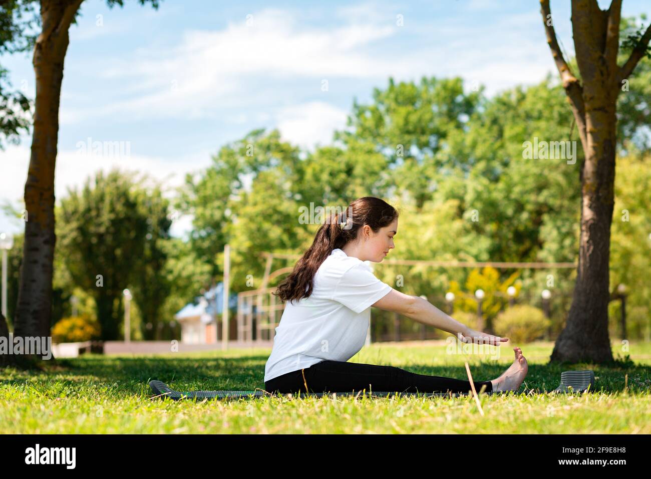 Yoga. A young woman in sports clothes, performs a tilt, sitting on a ...