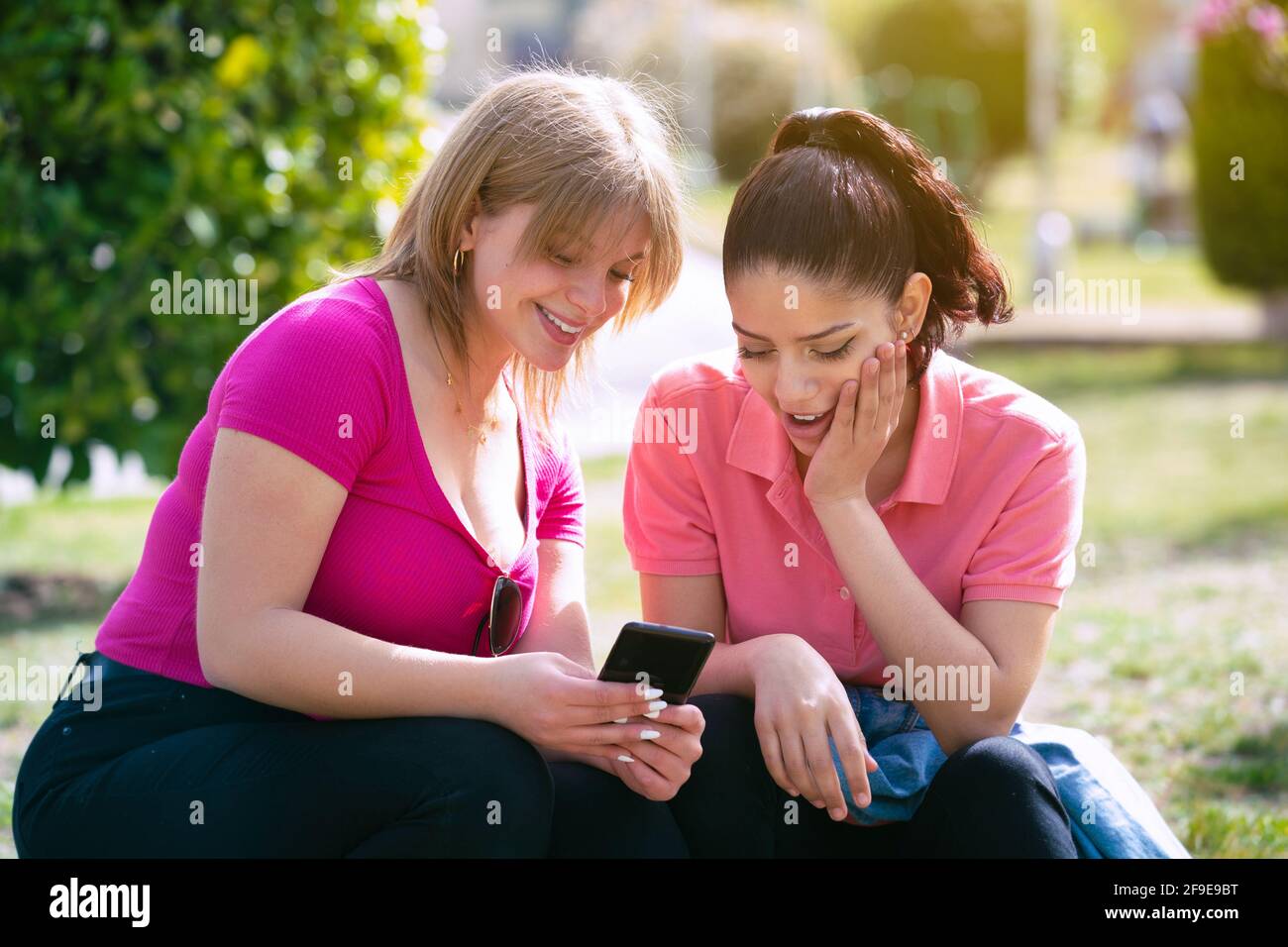 The two Spanish women in a park looking at the phone on a sunny day ...