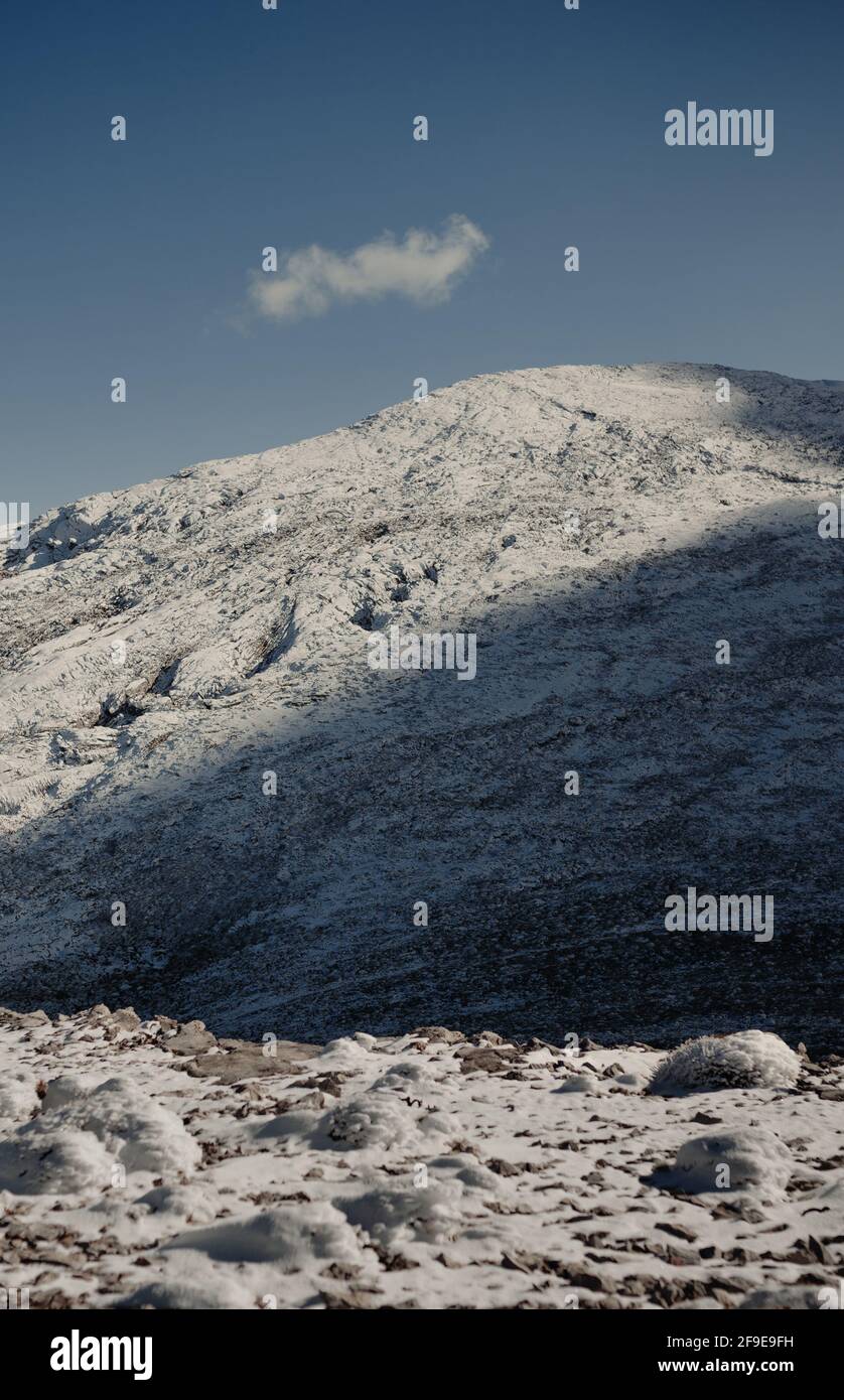 Picturesque view of mount with snow on bumpy surface under cloudy sky ...