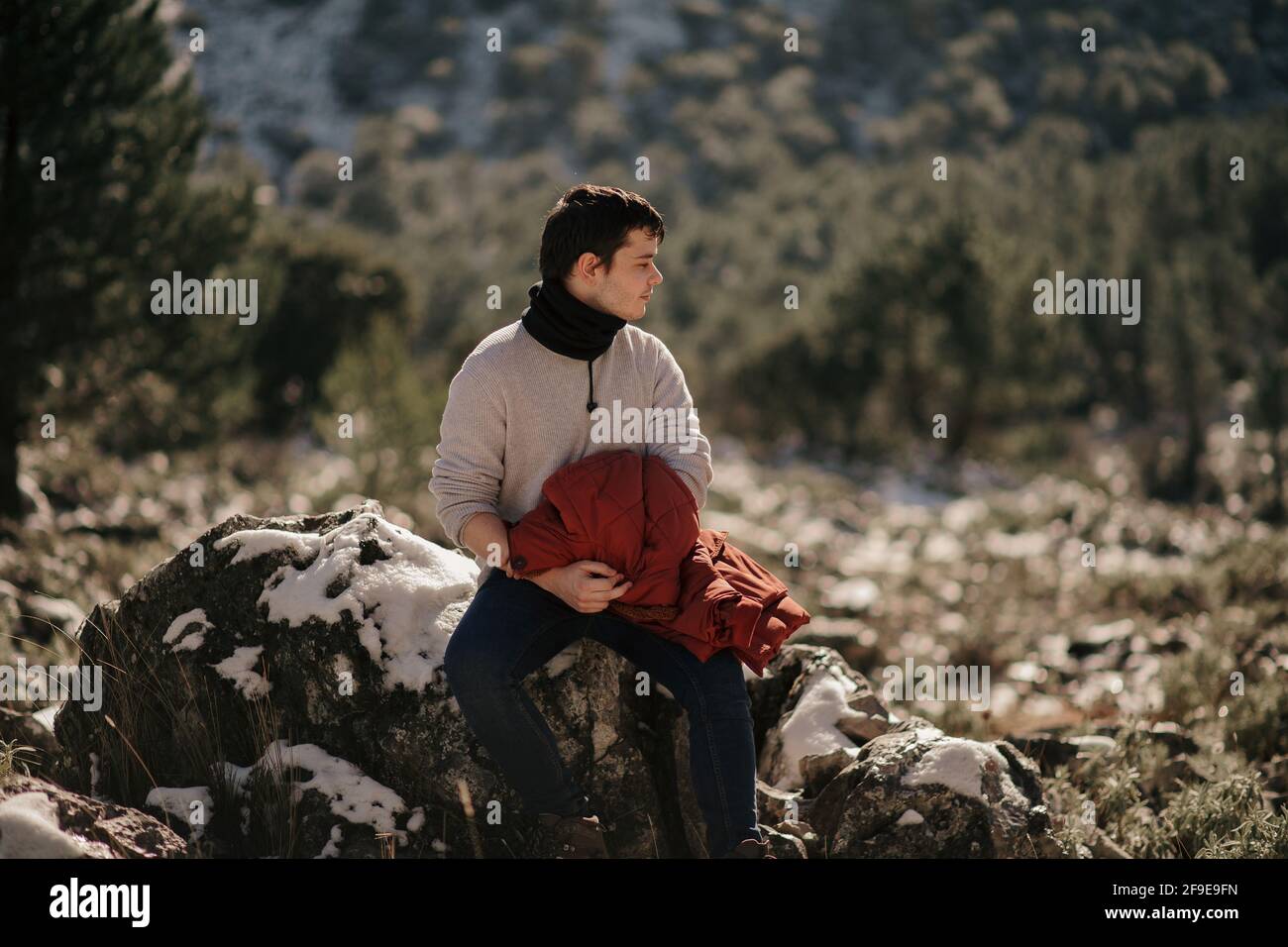 Young male tourist in warm clothes contemplating nature while sitting ...