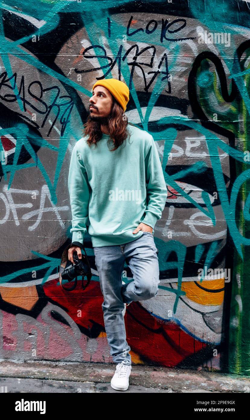 Black and white of unemotional female model in shirt touching hair with ...
