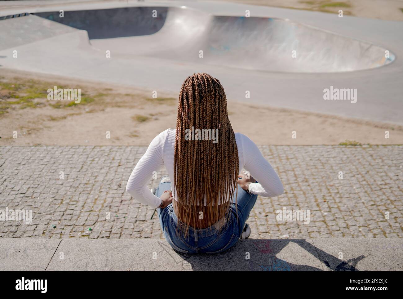 Back view black female with braided hairstyle and in rollerblades ...