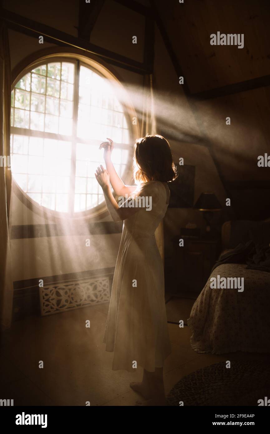 Side view of unrecognizable female in dress standing on couch against ...