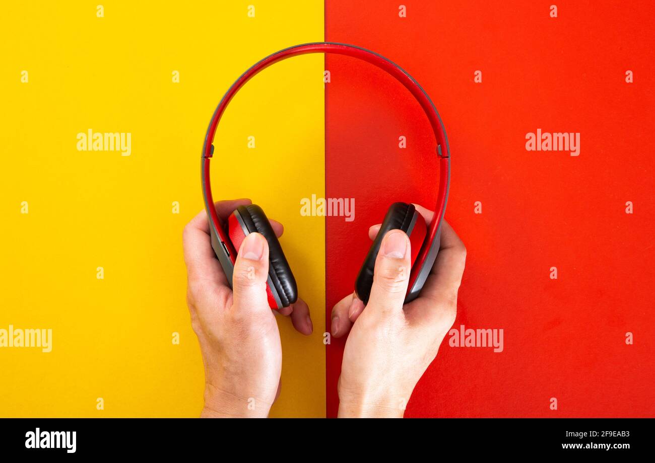 hand holding a headphones on red and yellow background. Music concept ...
