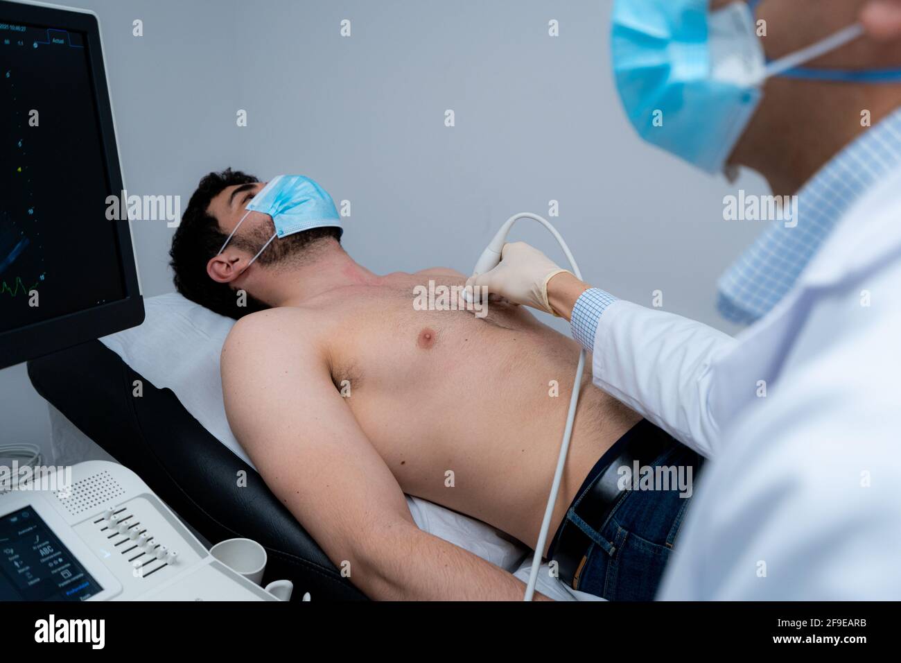 Side view of cropped unrecognizable male medic using modern ultrasound ...