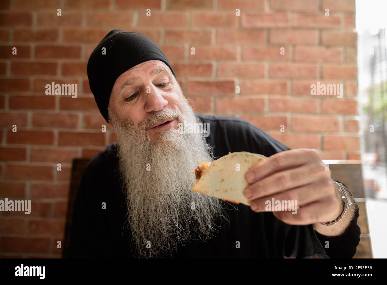 Portrait of mature man with long gray beard holding taco Stock Photo ...
