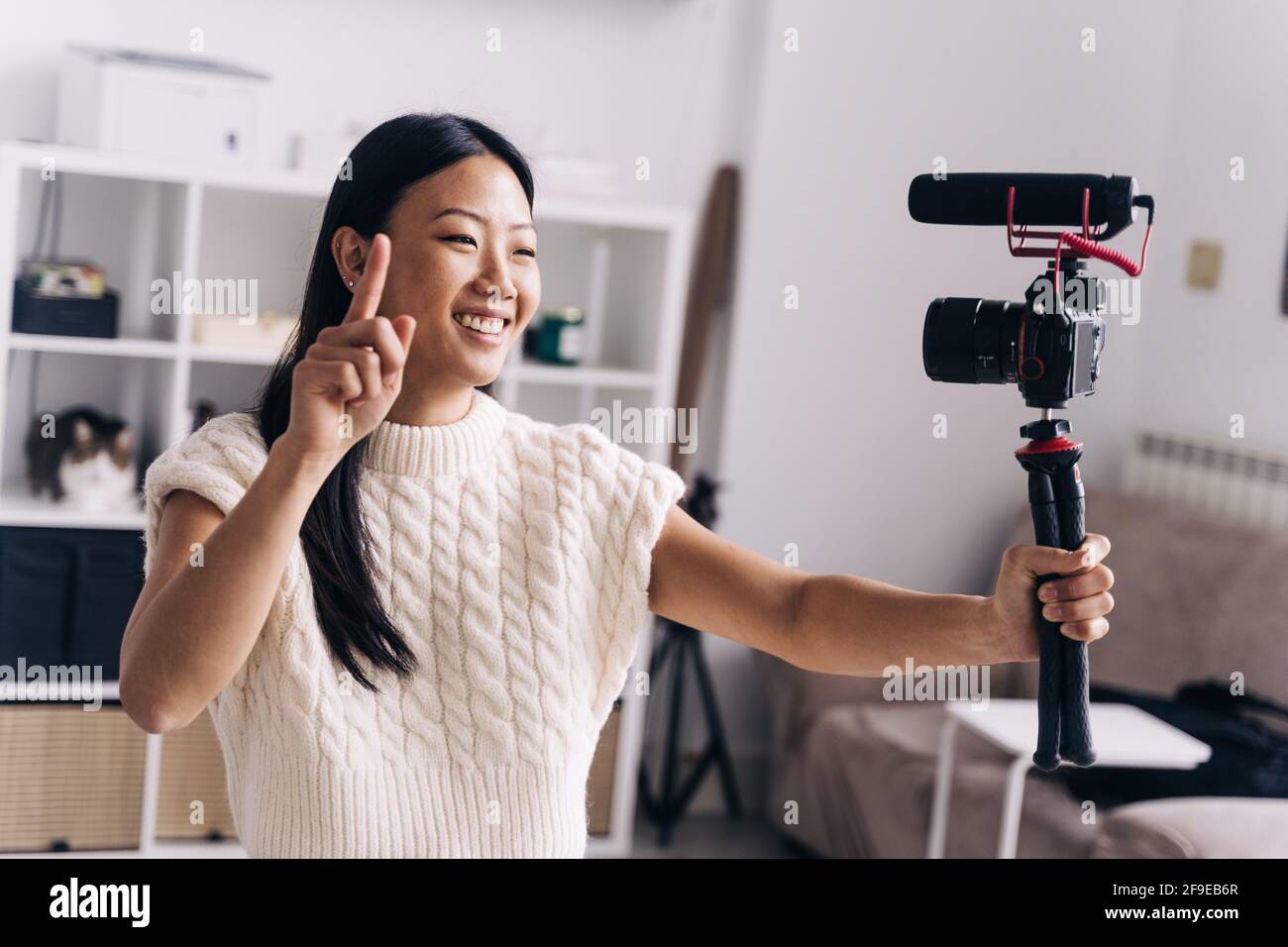 Smiling ethnic female vlogger recording video on photo camera while ...