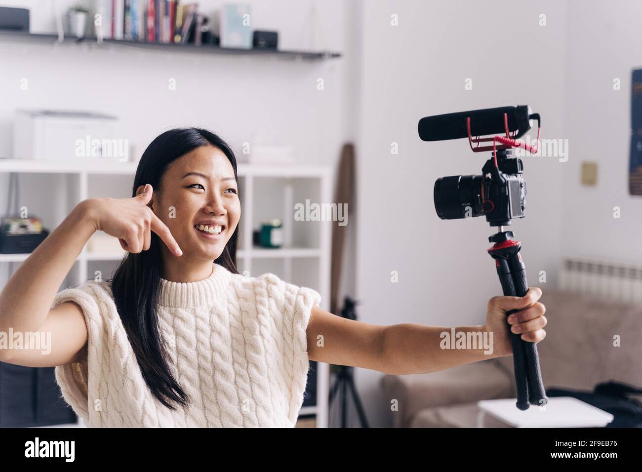 Smiling ethnic female vlogger recording video on photo camera while ...