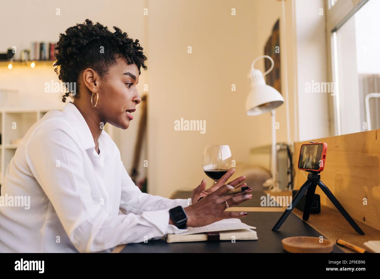 Side view of African American female writing in notebook while watching ...