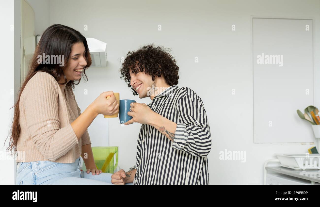 Side view of content Woman with boyfriend and cups of hot drinks ...
