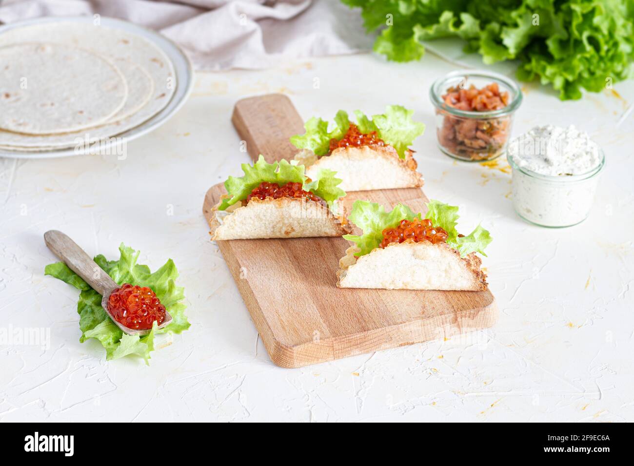 Small delicious tacos with red caviar and green lettuce served on ...