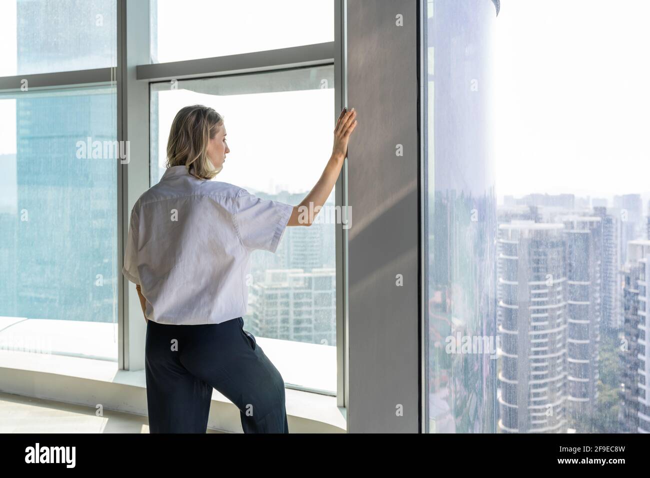 Back view of lonely girl in empty office watching the city from big ...