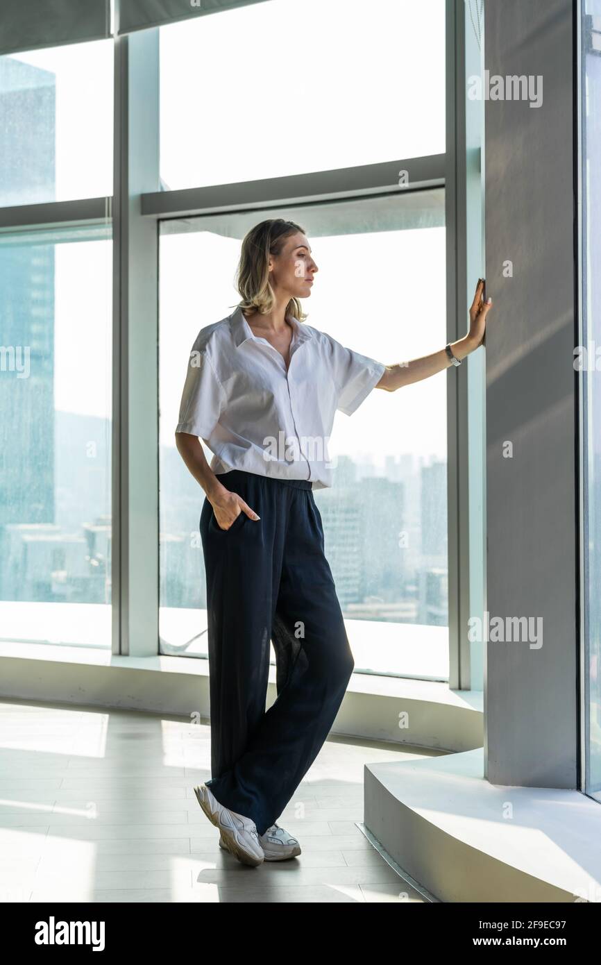 Lonely girl in empty office watching the city from big window Stock ...