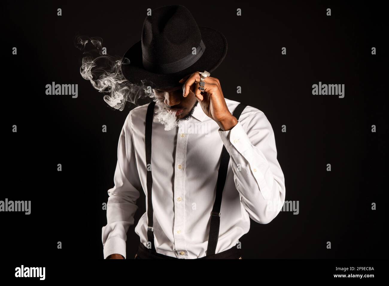 Masculine African American male in white shirt and hat exhaling vapor ...