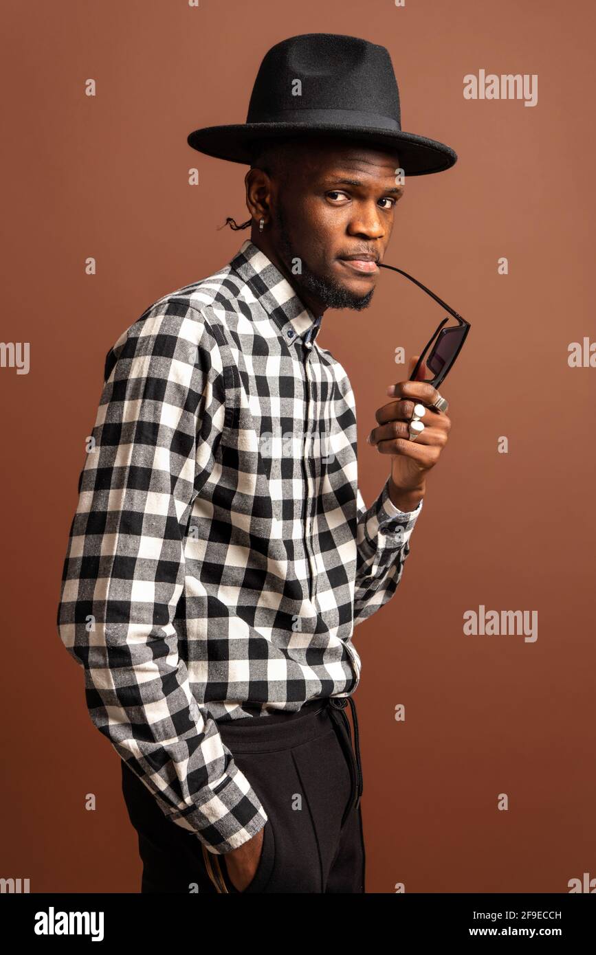 Young cool African American male model in checkered shirt and hat ...