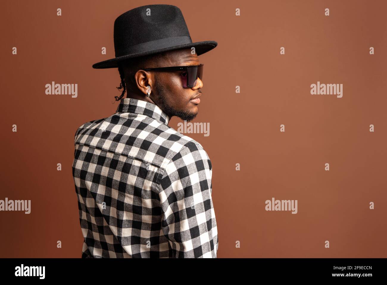 Young cool African American male model in checkered shirt, hat and ...