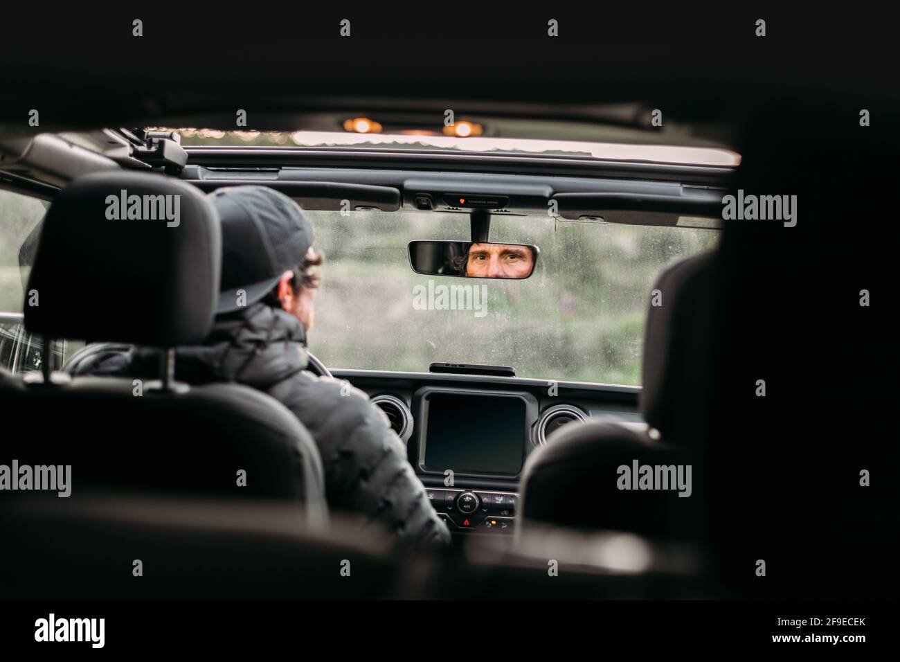 Back view of bearded man driving car and looking at the camera through ...