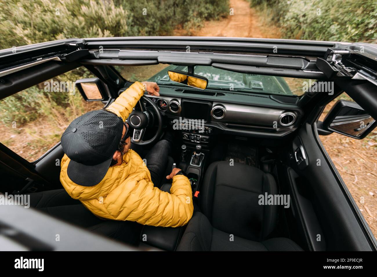 From above inside view of a driver wearing a cap and sunglasses in an ...