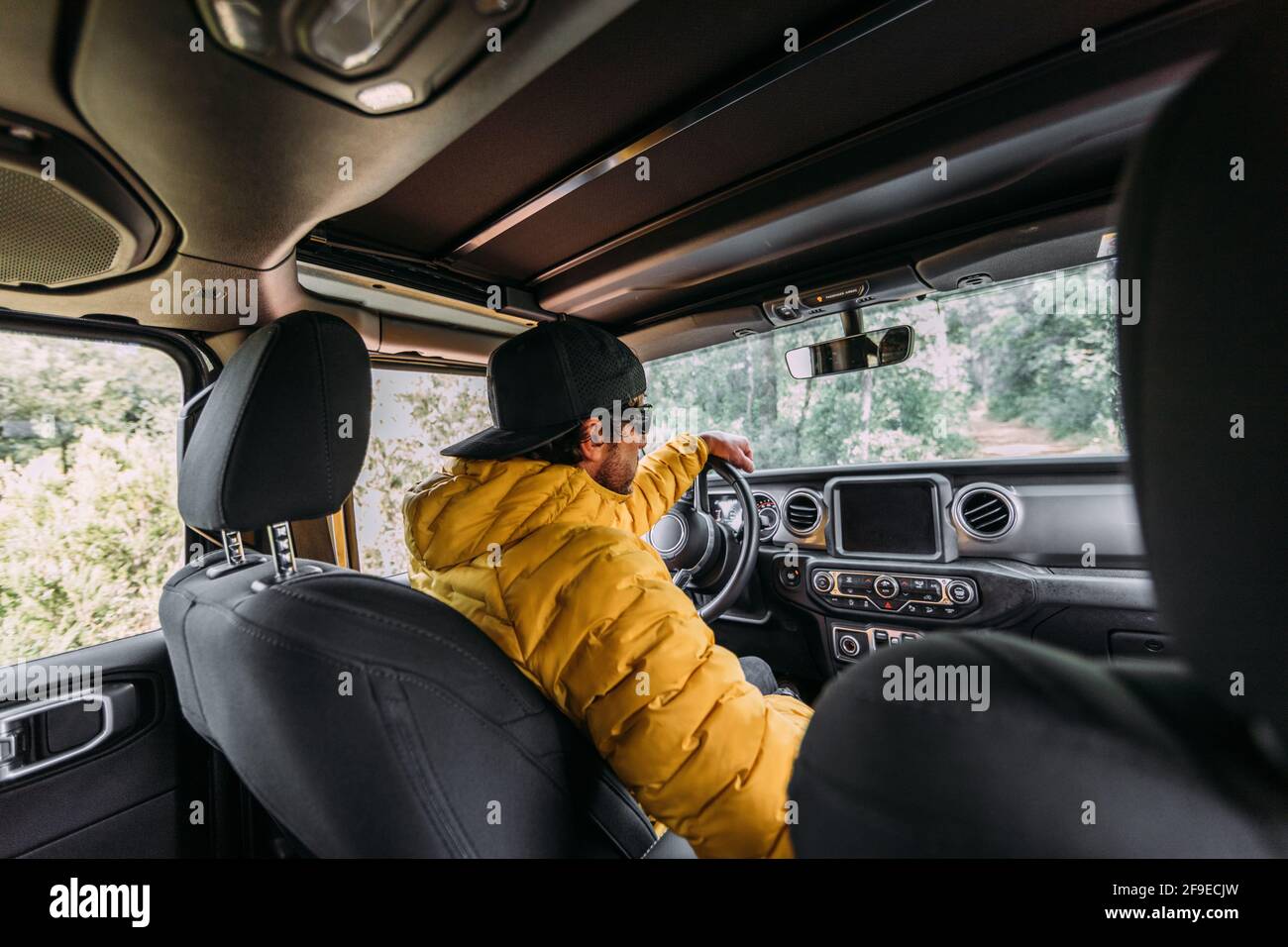From behind inside view of a driver wearing a cap and sunglasses in an ...