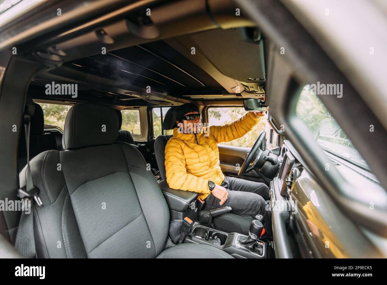 Inside view of a driver wearing a cap and sunglasses in an off-road car ...