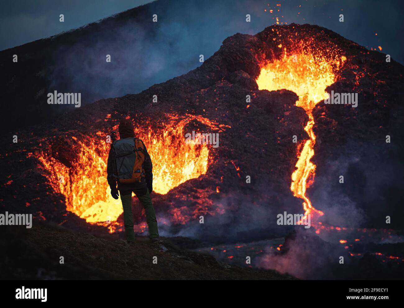 man explorer observing the magma sparks out of the volcano ...