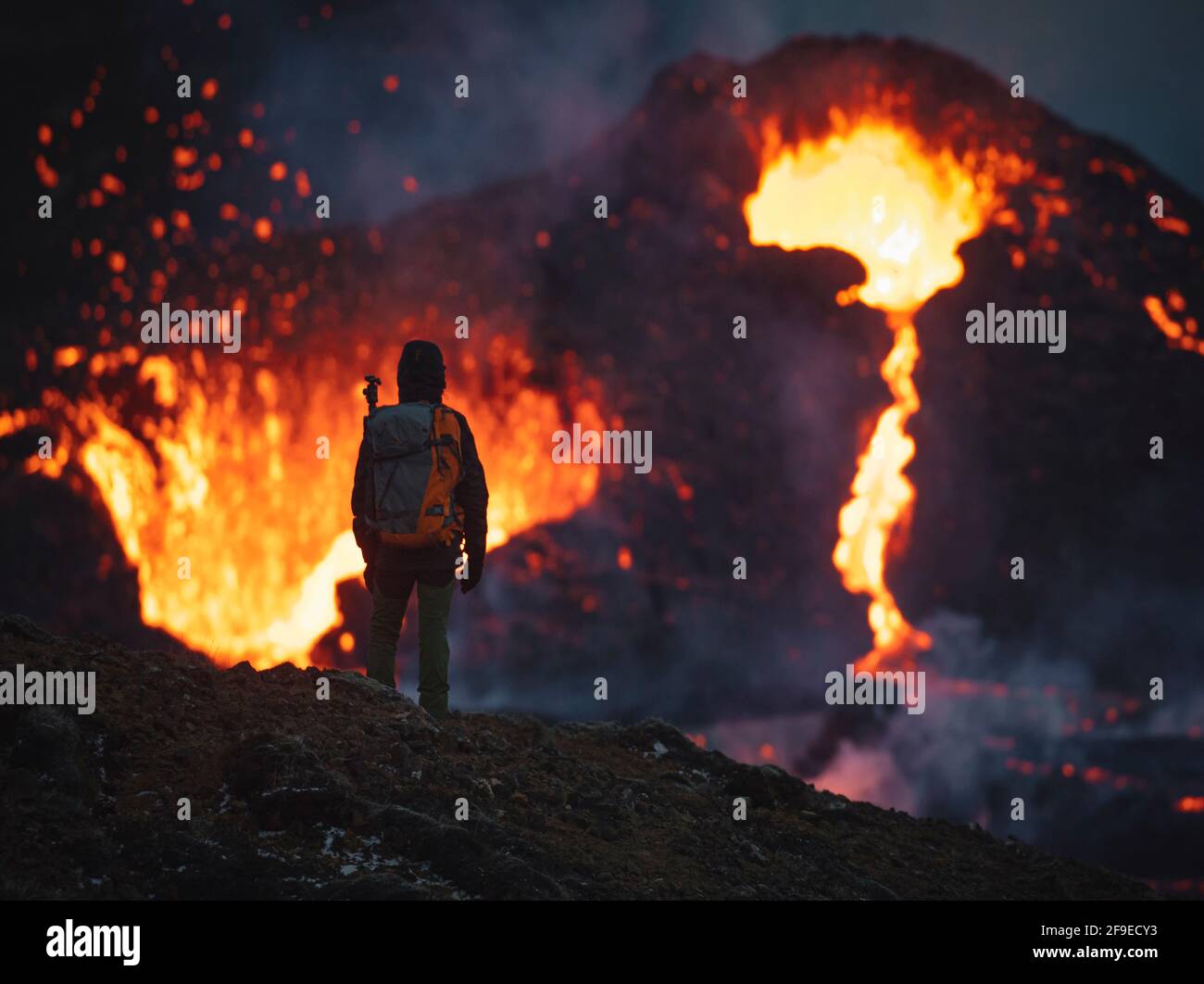 man explorer observing the magma sparks out of the volcano ...