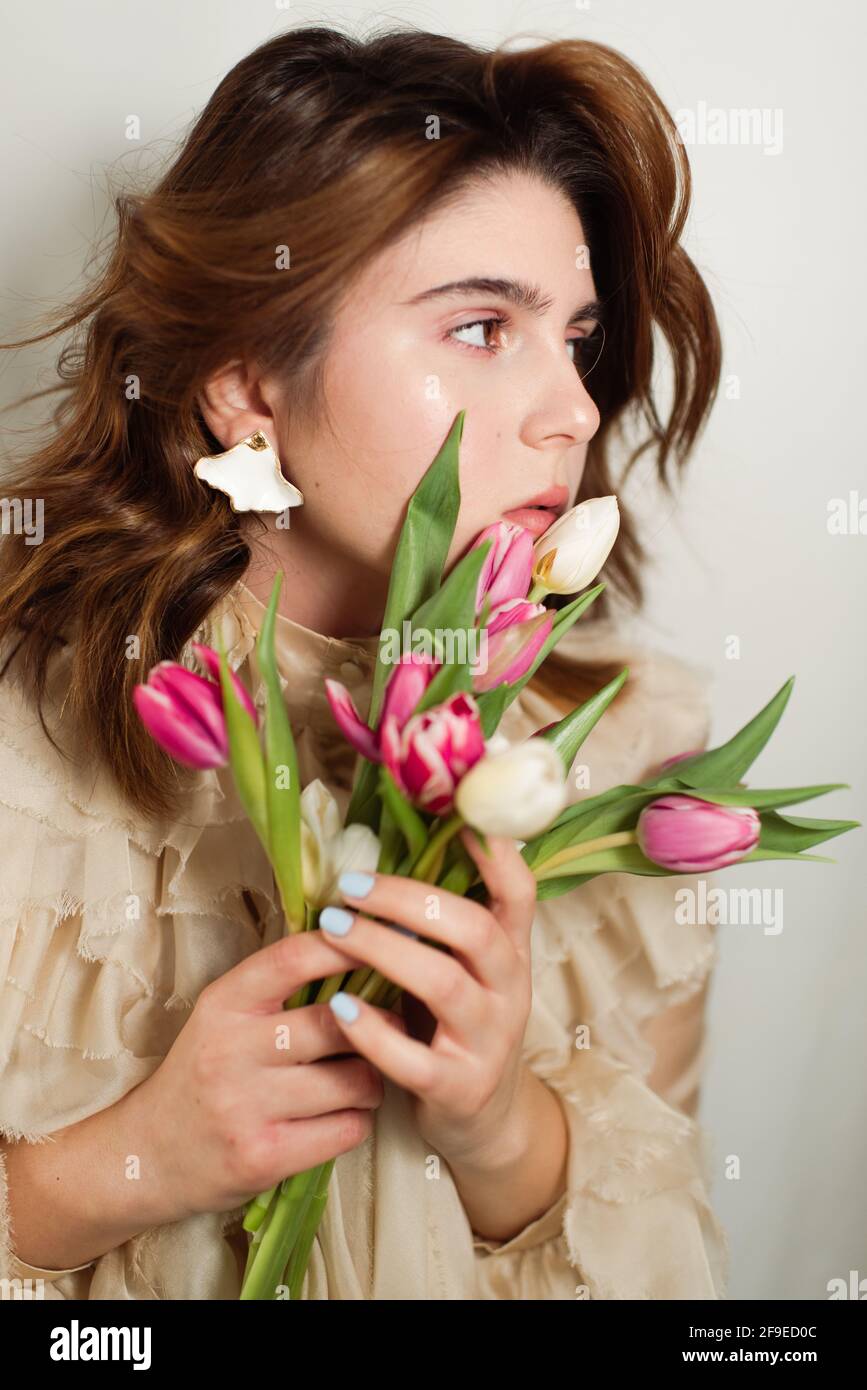 Tranquil female in hat and sweater standing with bouquet of aromatic ...