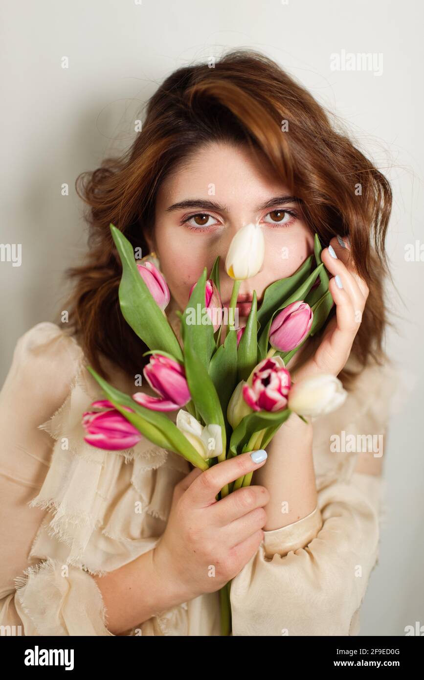 Tranquil female in hat and sweater standing with bouquet of aromatic ...