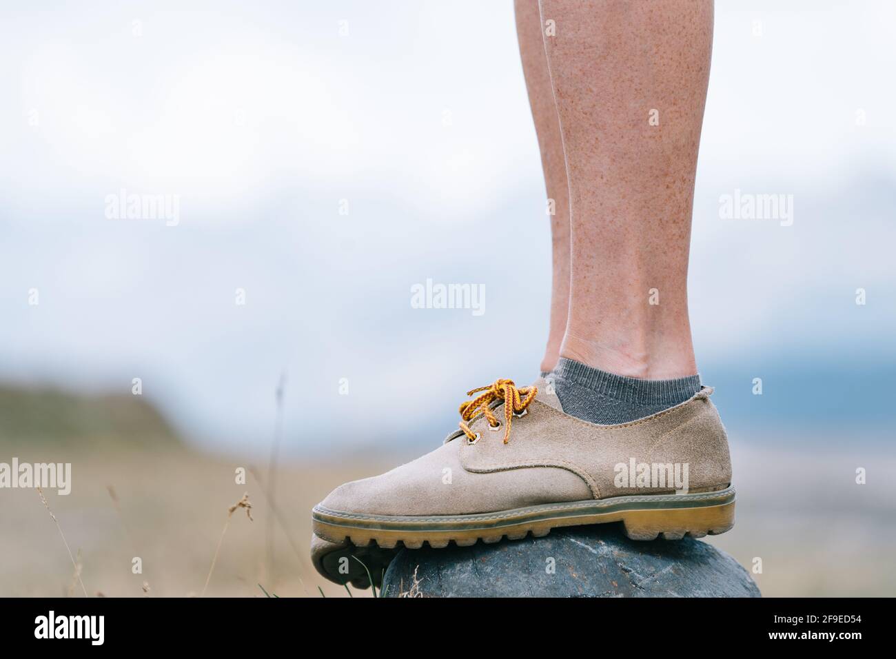 Side view of crop female hiker in boots standing on rock in nature ...