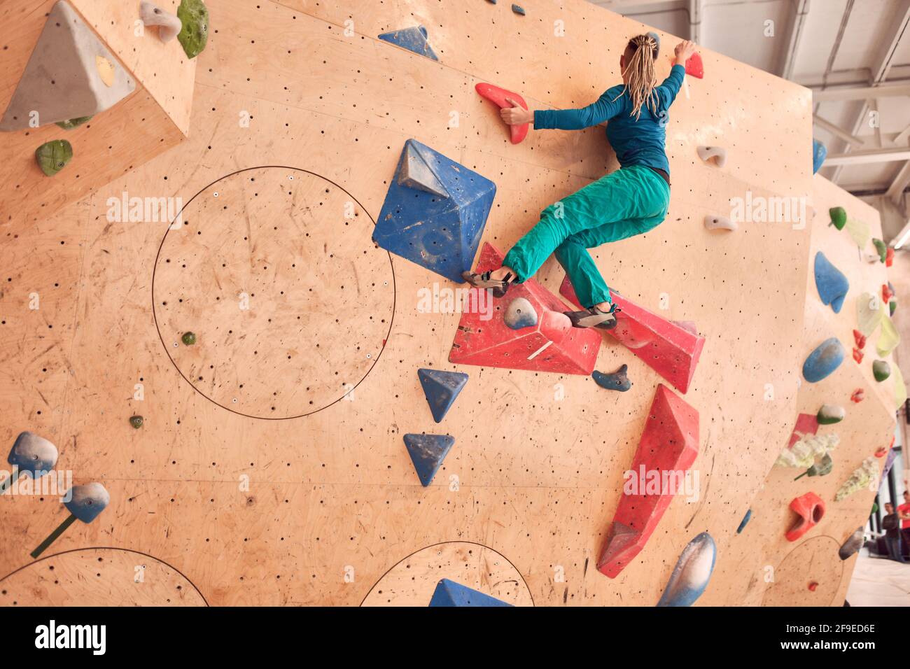 Low angle back view of anonymous female athlete climbing artificial ...