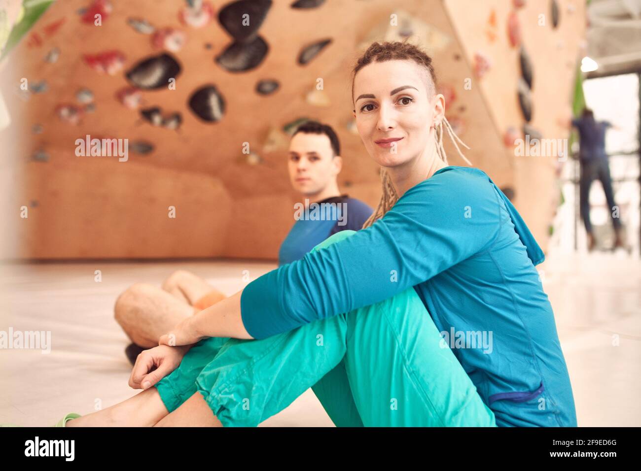 Side view of female and male climbers sitting on floor near artificial ...