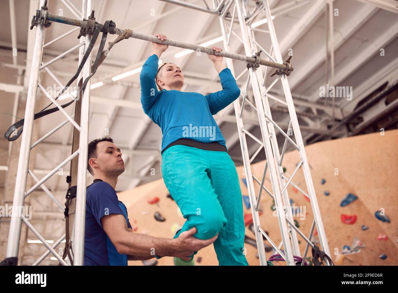 From below of female doing pull ups on horizontal bar with help of ...