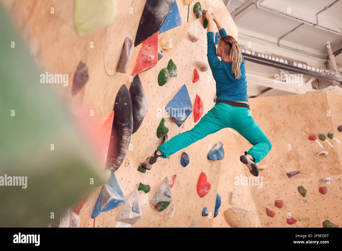 Low angle back view of anonymous female athlete climbing artificial ...