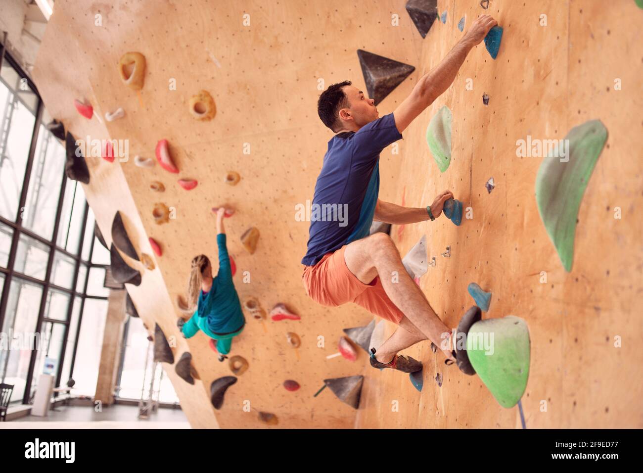 Side view of strong male and female climbers climbing artificial wall ...