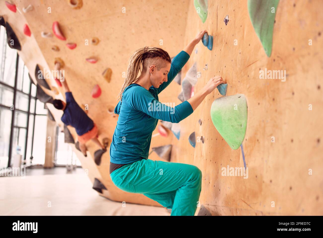 Side view of strong male and female climbers climbing artificial wall ...
