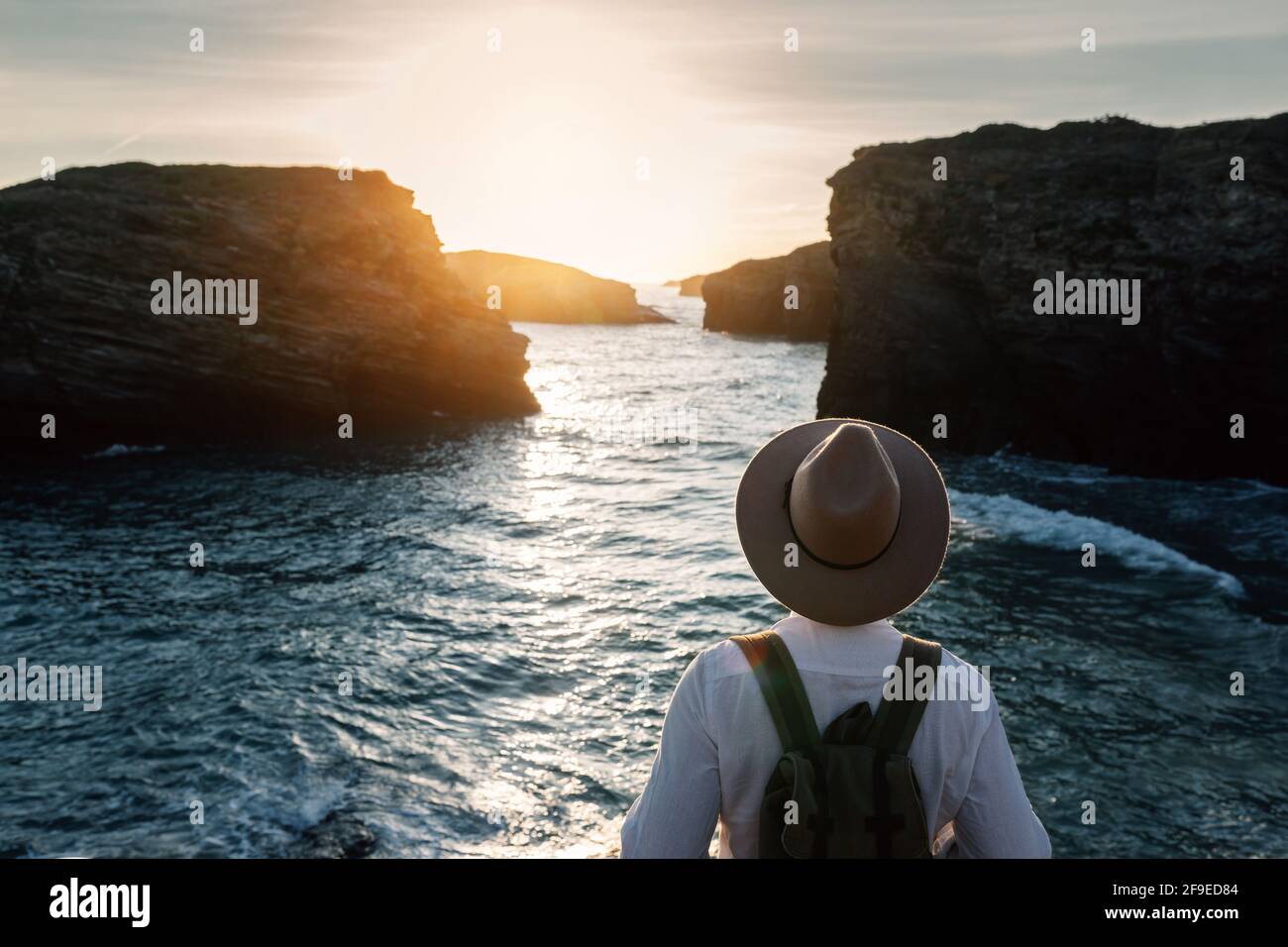 man with backpack and hat standing and looking at the sea Stock Photo ...