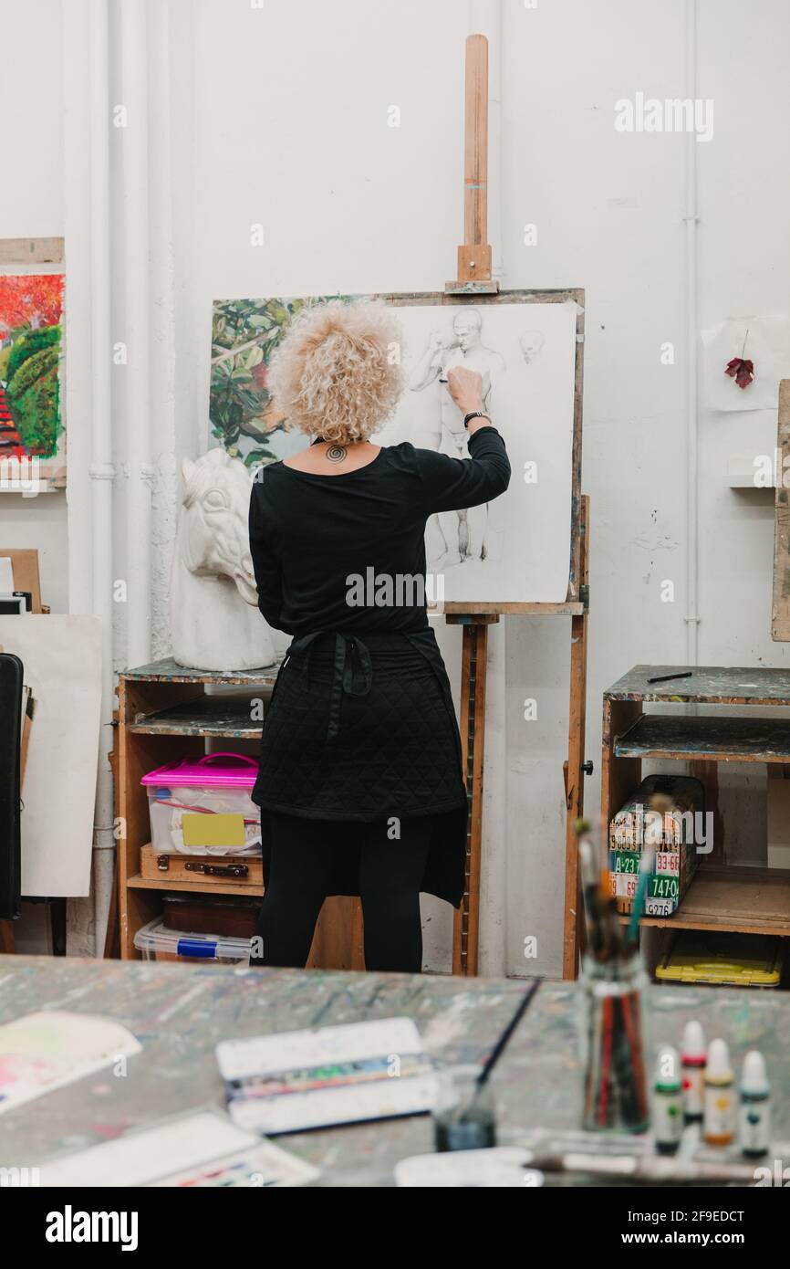 Back view of anonymous female artist creating drawing of human with ...