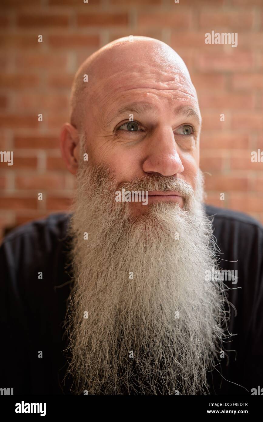 Portrait of happy mature man smiling and thinking with long gray beard ...
