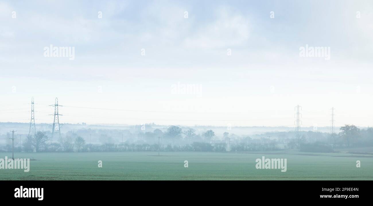 National grid electricity pylons in a UK landscape on a misty morning ...
