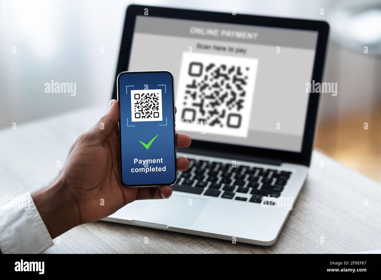 Black man scanning barcode from laptop using smartphone Stock Photo - Alamy