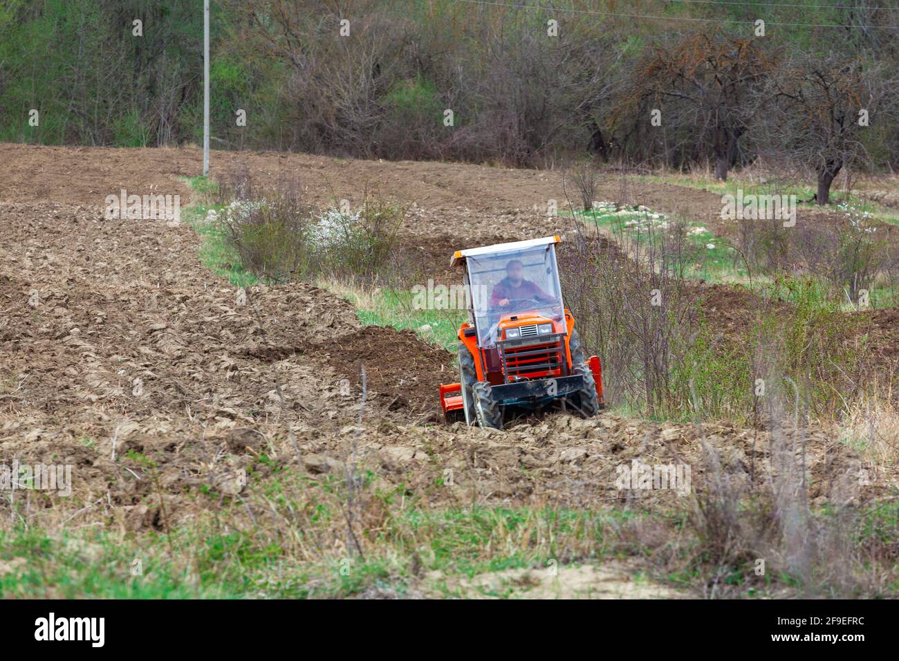 A small tractor cultivates the land for sowing. Agriculture Stock Photo ...