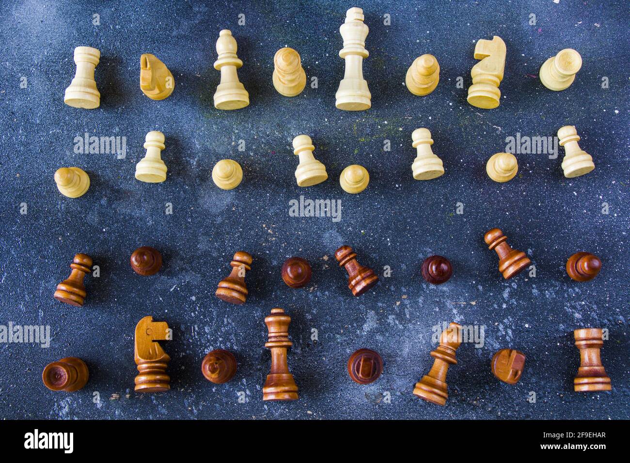 A top view of fallen and standing wooden chess figures on a blue dotted ...