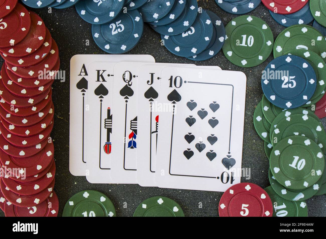 A top view of spade royal flush cards and poker chips on a dark dotted ...
