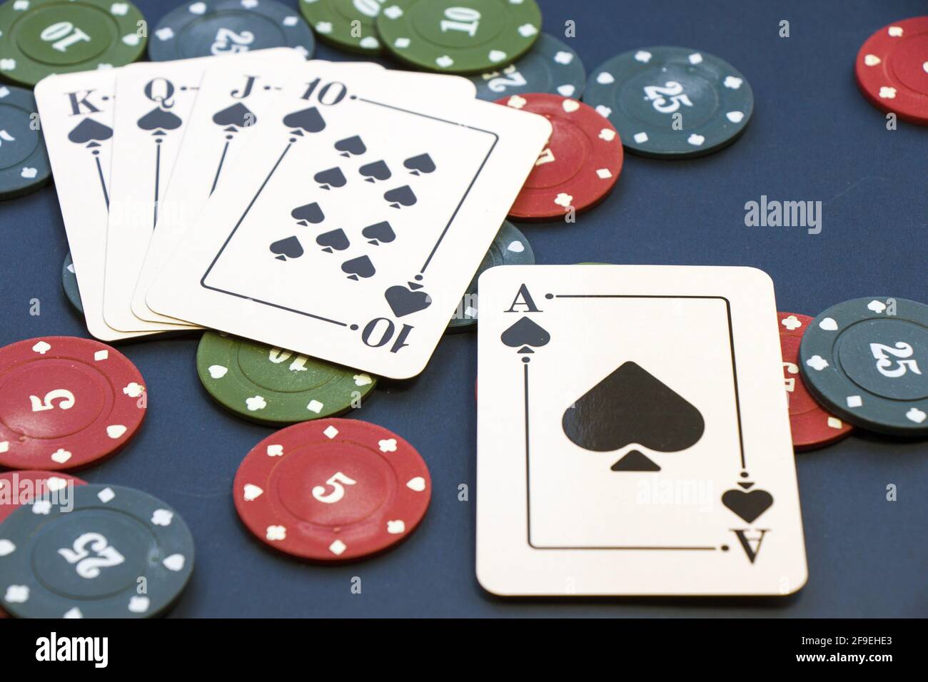 A closeup shot of spade royal flush cards and poker chips on the blue ...