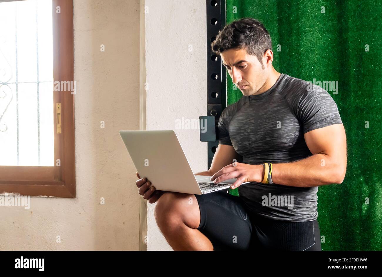 Latino coach in sportswear working out in gym with computer preparing ...