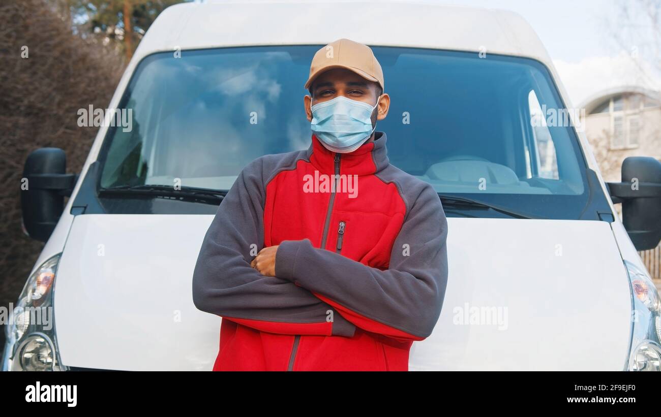 Delivery man with face mask and crossed hands standing in front of the ...