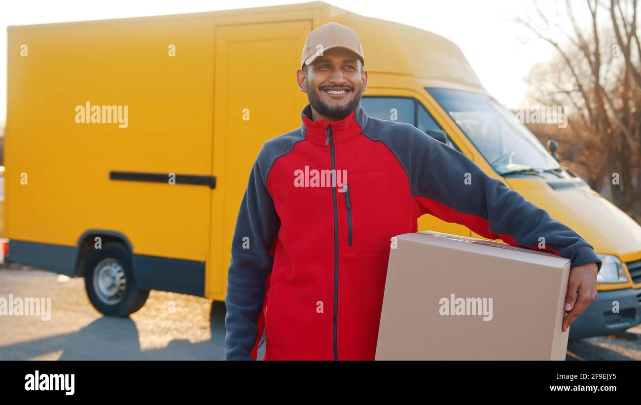 Indian man delivering package. Holding cardboard box in front of the ...