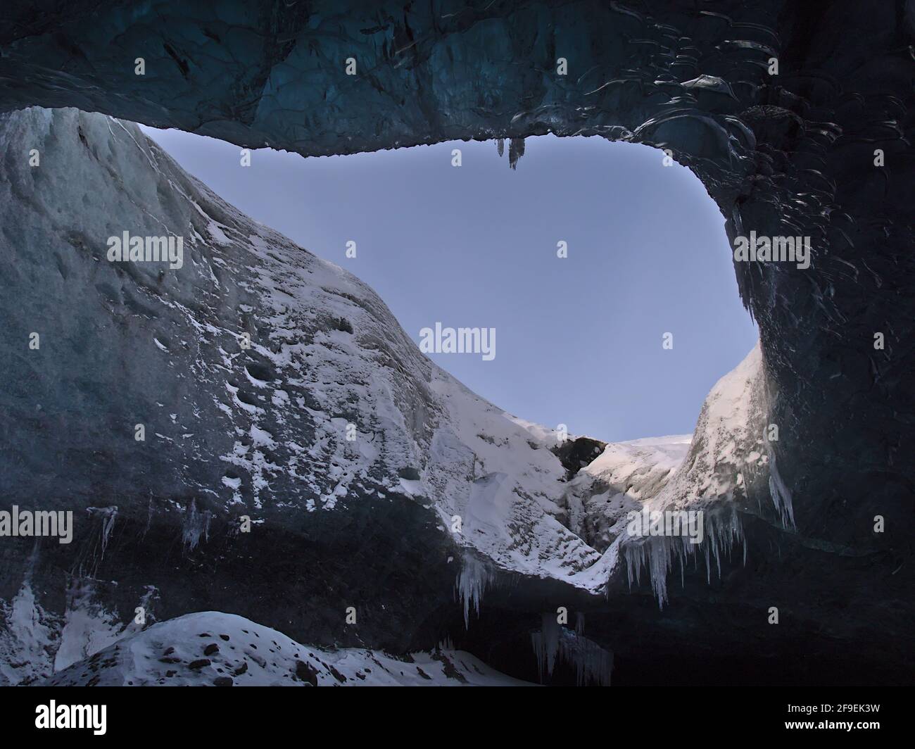 Low angle view of a big moulin hole with icicles in the ceiling of the ...